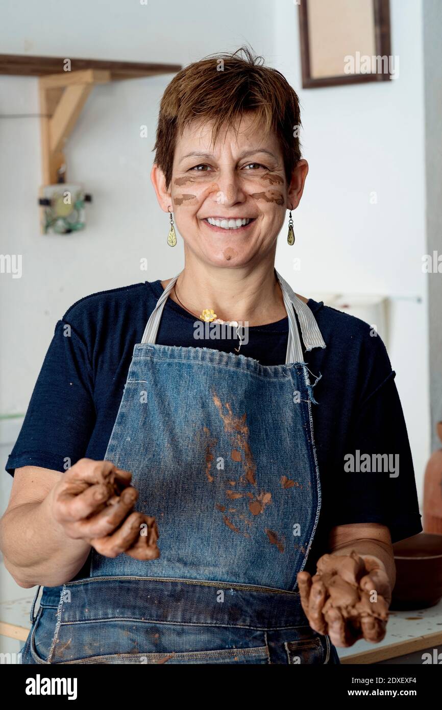 Playful female potter with mud over face at ceramic workshop Stock ...