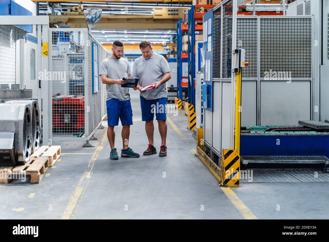 Professional male engineers discussing while standing in industry Stock ...