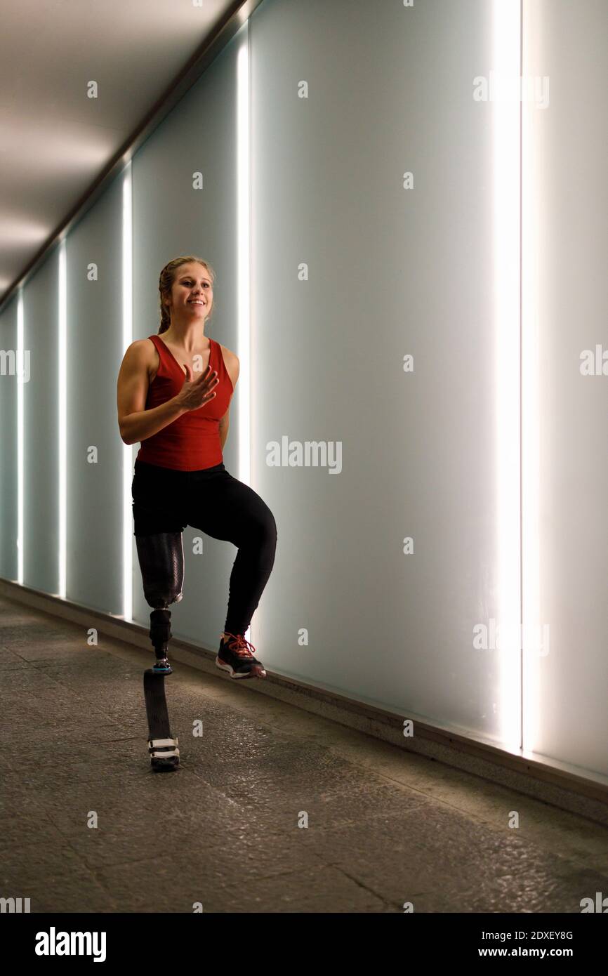 Young athlete with artificial leg running while exercising in underpass ...