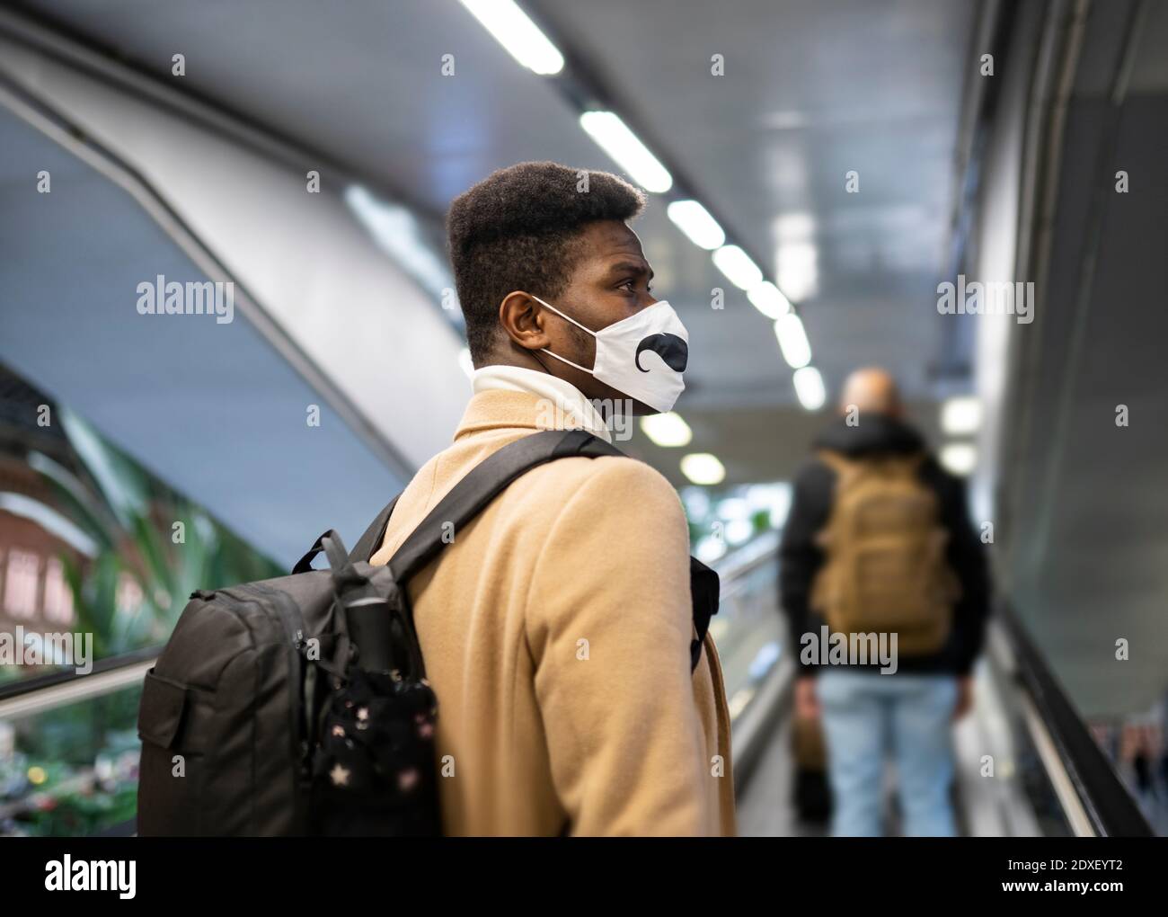 Young man wearing face mask standing on escalator at station Stock ...