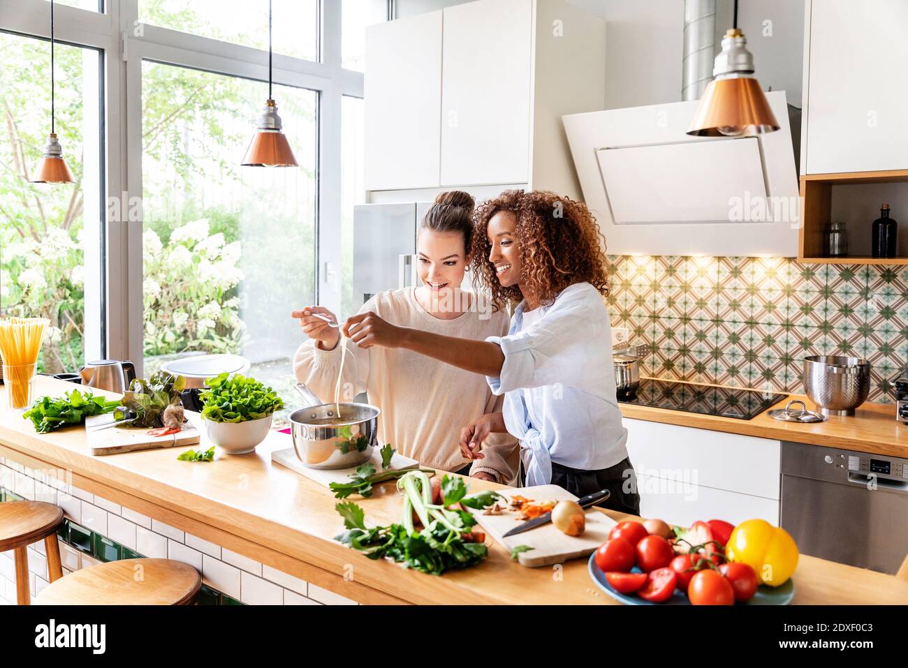 Female coworkers cooking spaghetti together at work place kitchen Stock ...