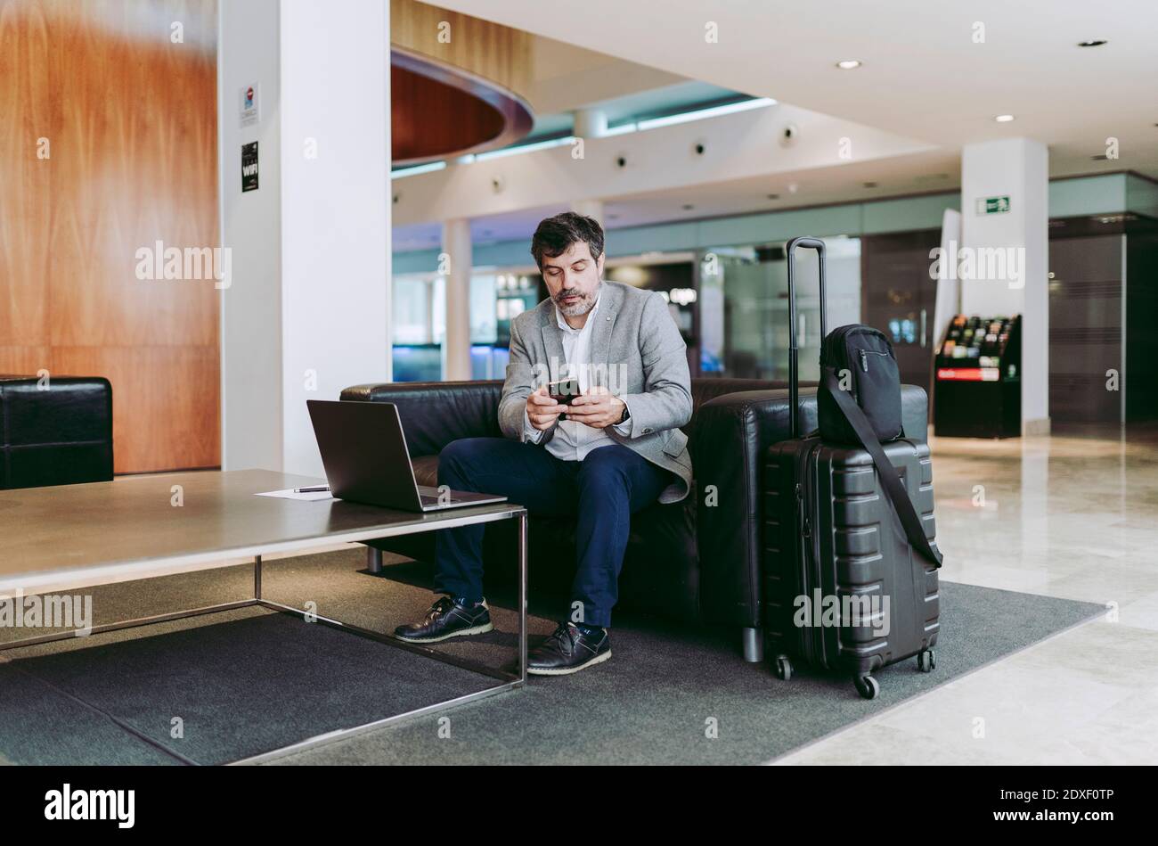 Male professional using mobile phone while sitting in hotel lobby Stock ...