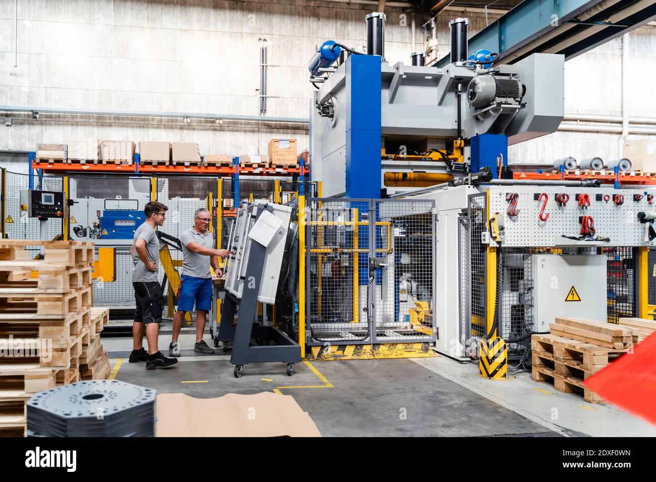 Mature and young male coworkers testing machine at factory Stock Photo ...