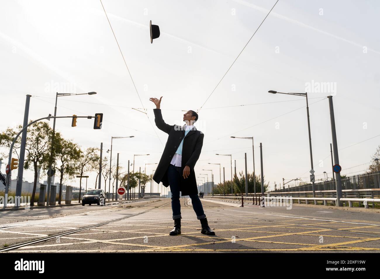 Young man throwing his hat in air on street during sunny day Stock ...