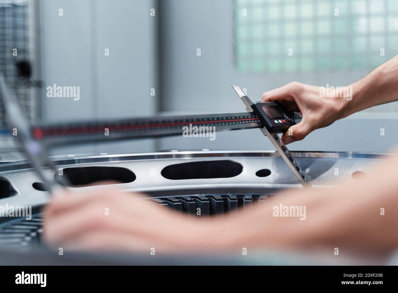 Mature male engineer's hands measuring machine with measurement tool at ...