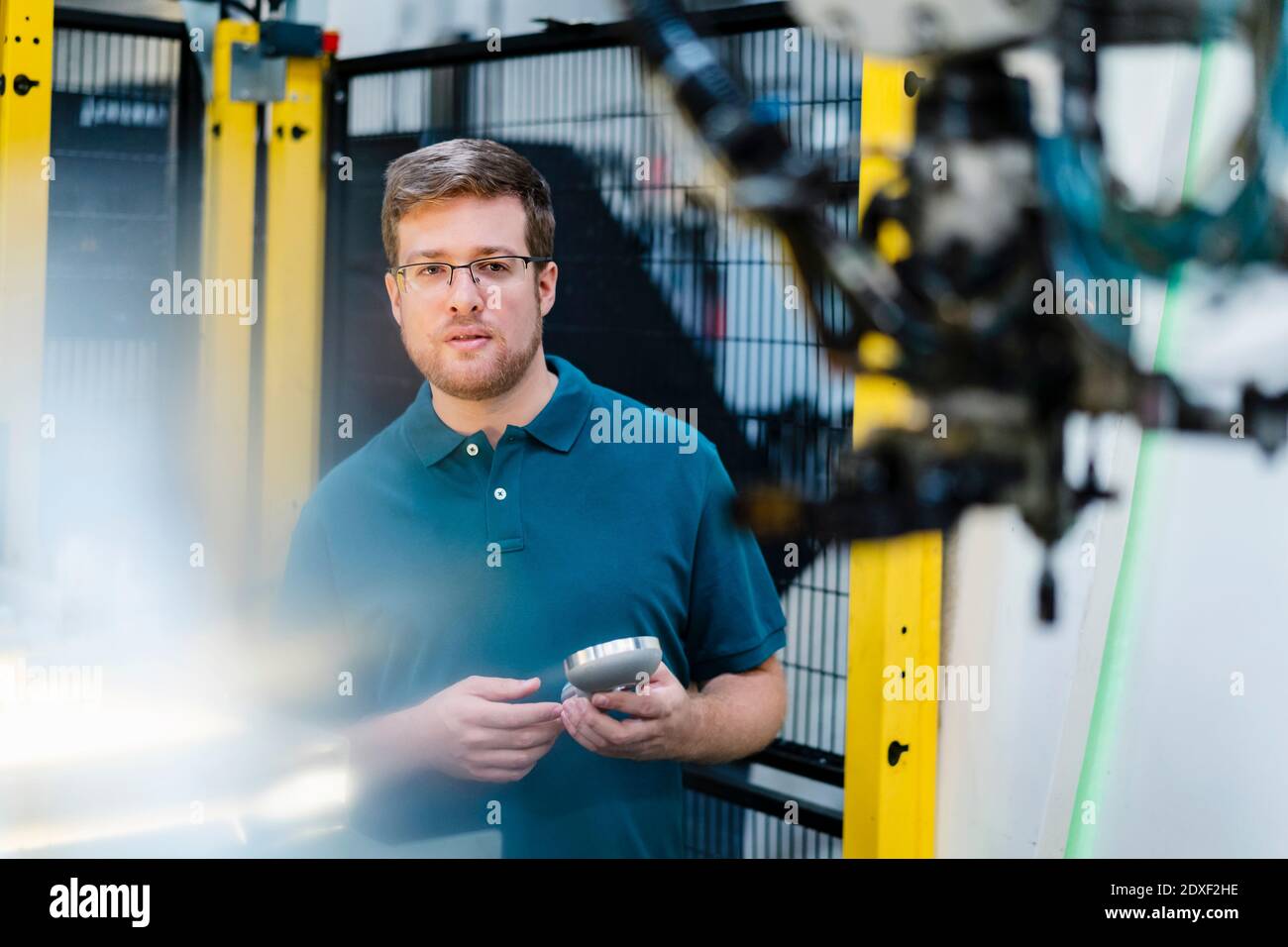 Male worker holding machine part while standing at industry Stock Photo ...