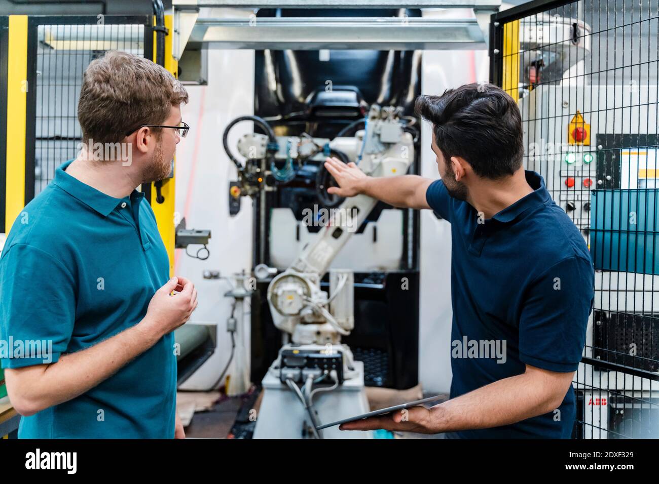 Male coworkers discussing while standing in manufacturing factory Stock ...