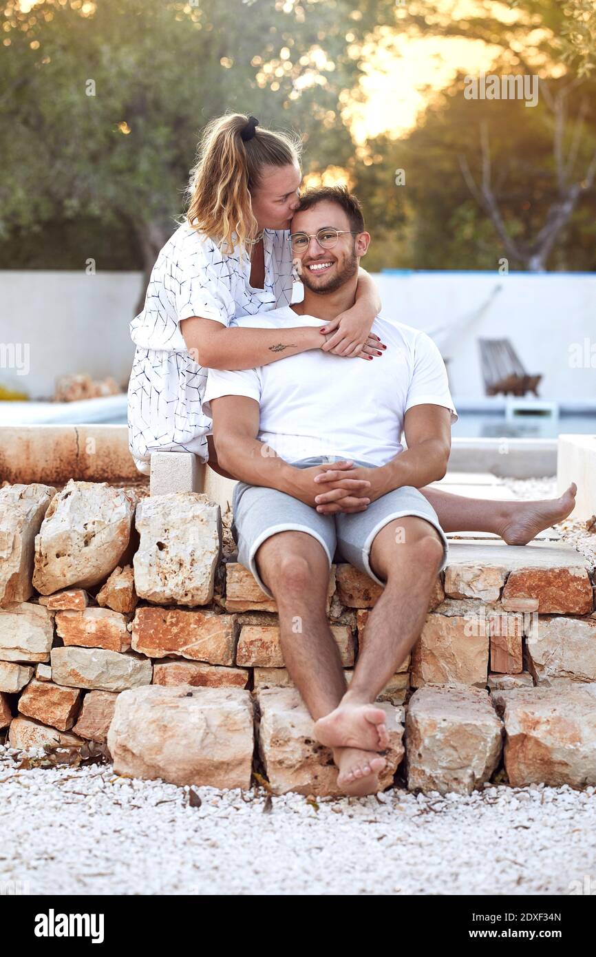 Girlfriend kissing boyfriend on forehead while sitting on stone steps ...