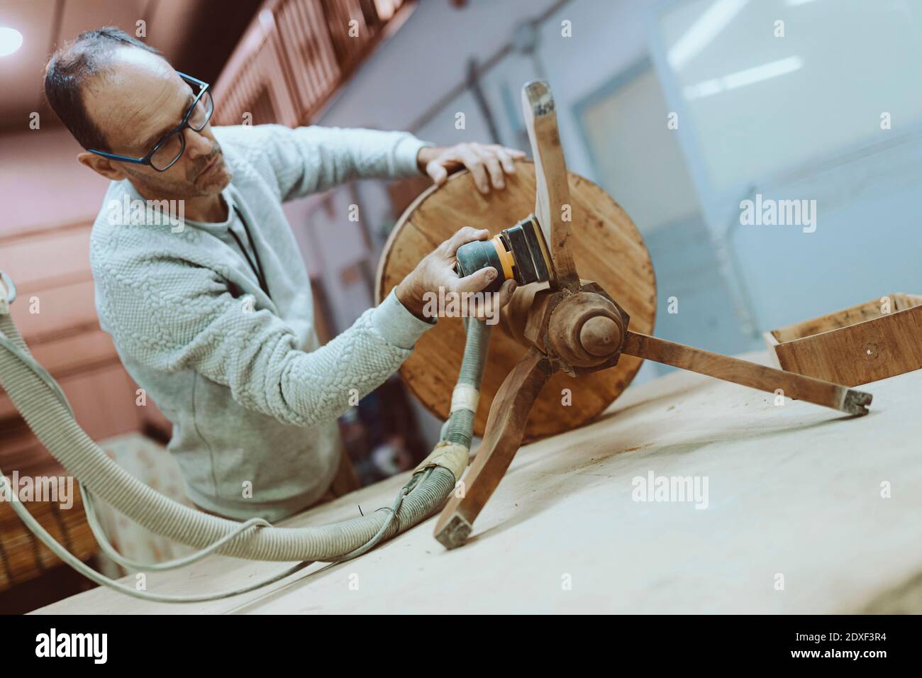 Craftsman using sander on table while standing at workshop Stock Photo ...