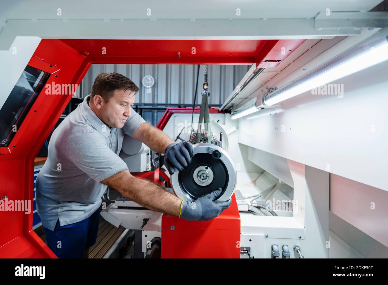 Professional male engineer testing machine at illuminated industrial ...