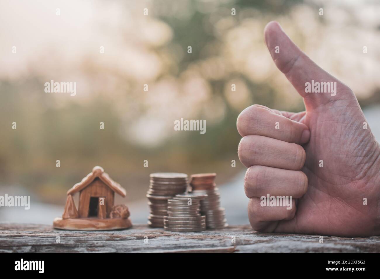 Hand Thump up success with coins stack home model on wood table ...