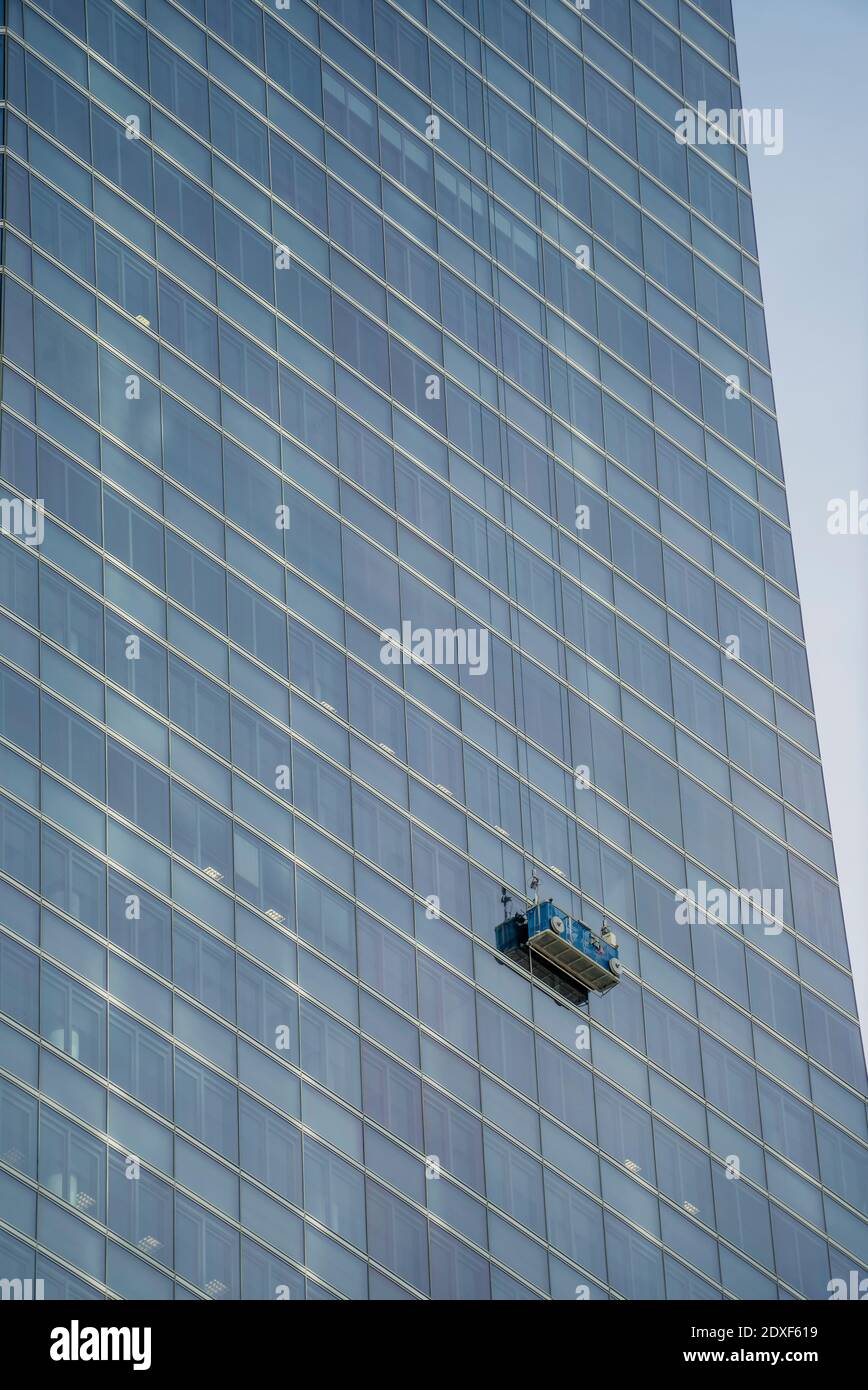Spain, Madrid, Window cleaners platform hanging in front of skyscraper ...