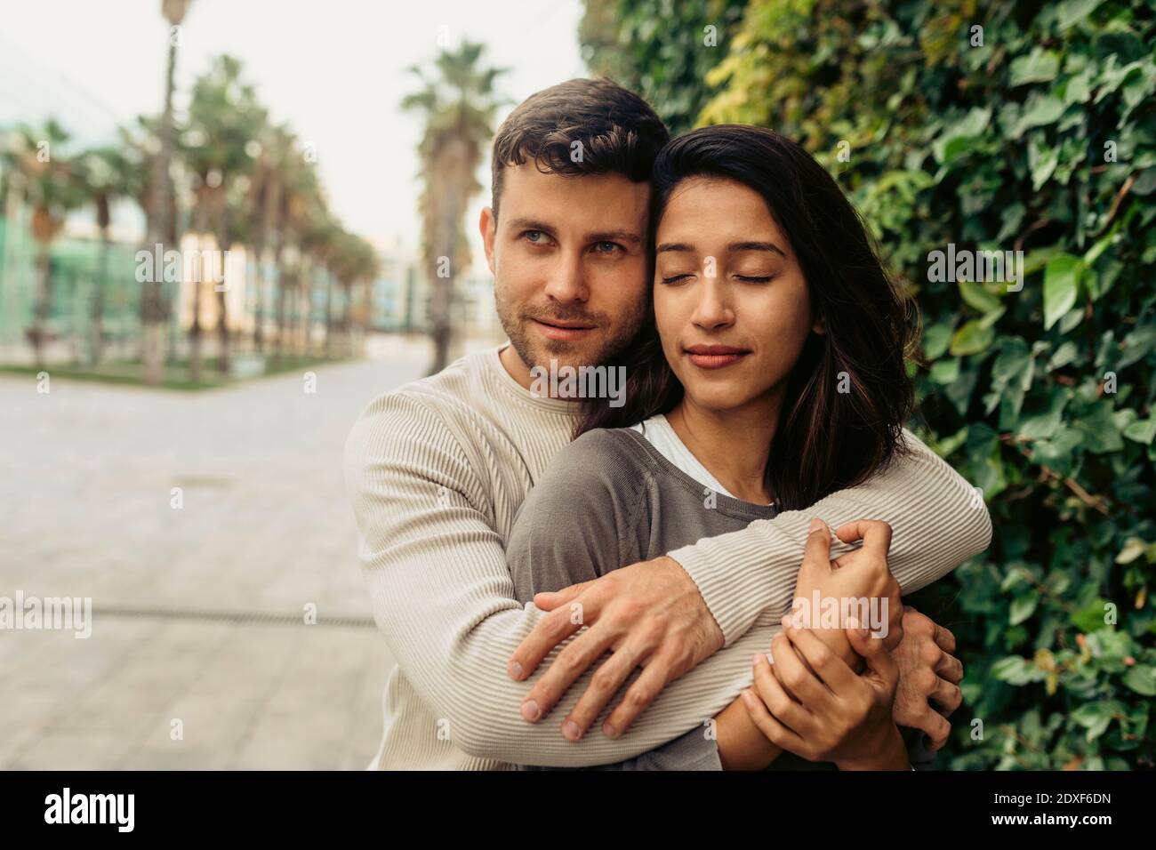 Young romantic couple embracing while standing in park Stock Photo - Alamy