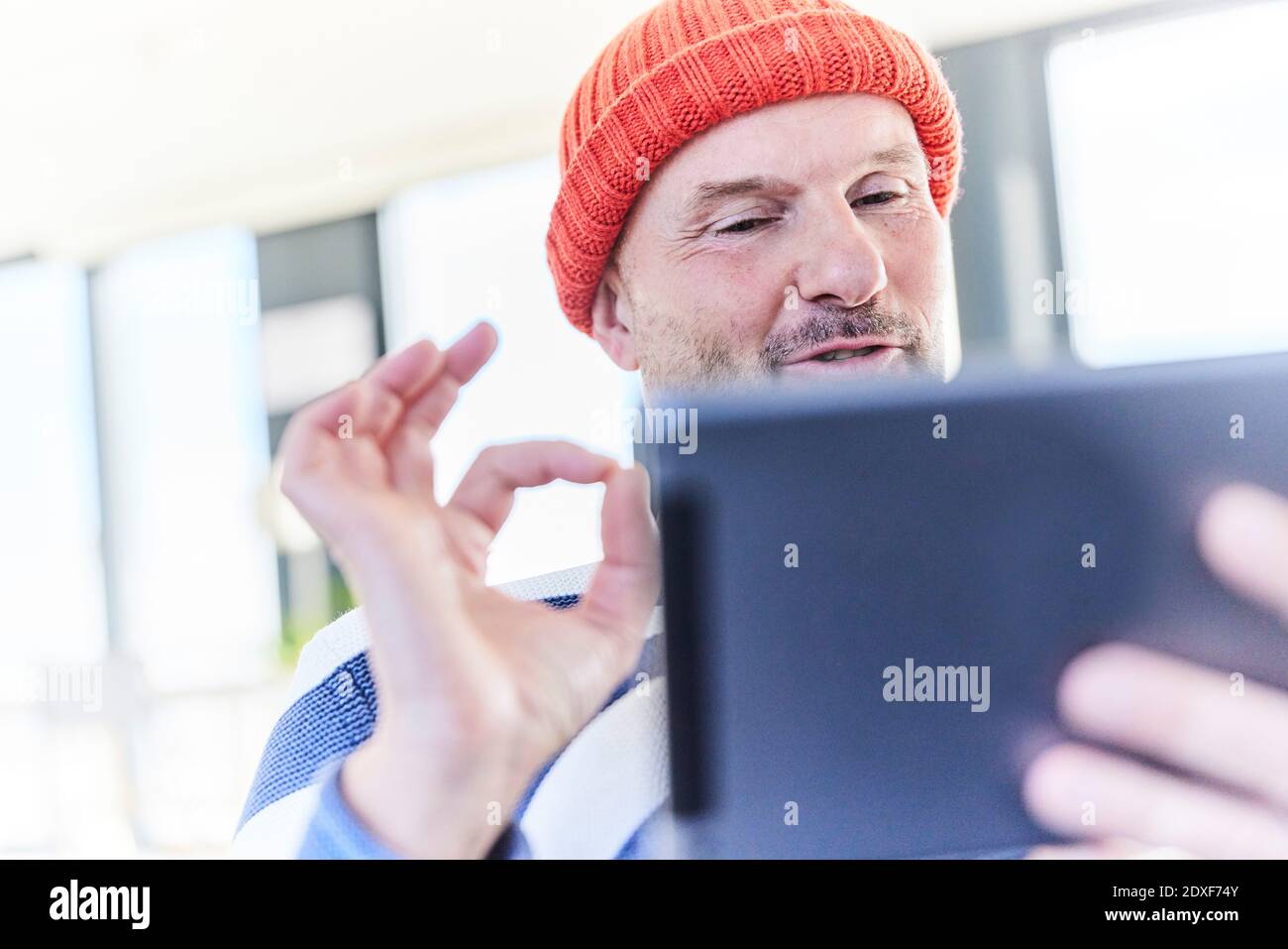 Mature man showing OK hand sign while talking to video call on digital ...