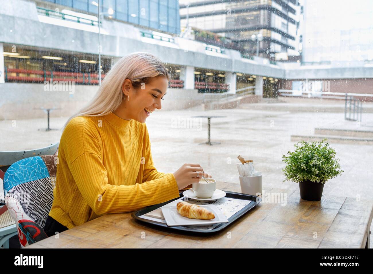 Happy young woman having breakfast at cafe during rainy season Stock ...