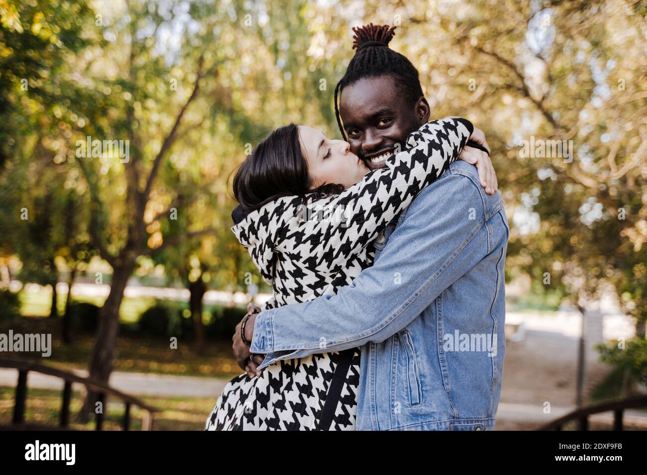 Heterosexual couple kissing and embracing while standing in park Stock ...