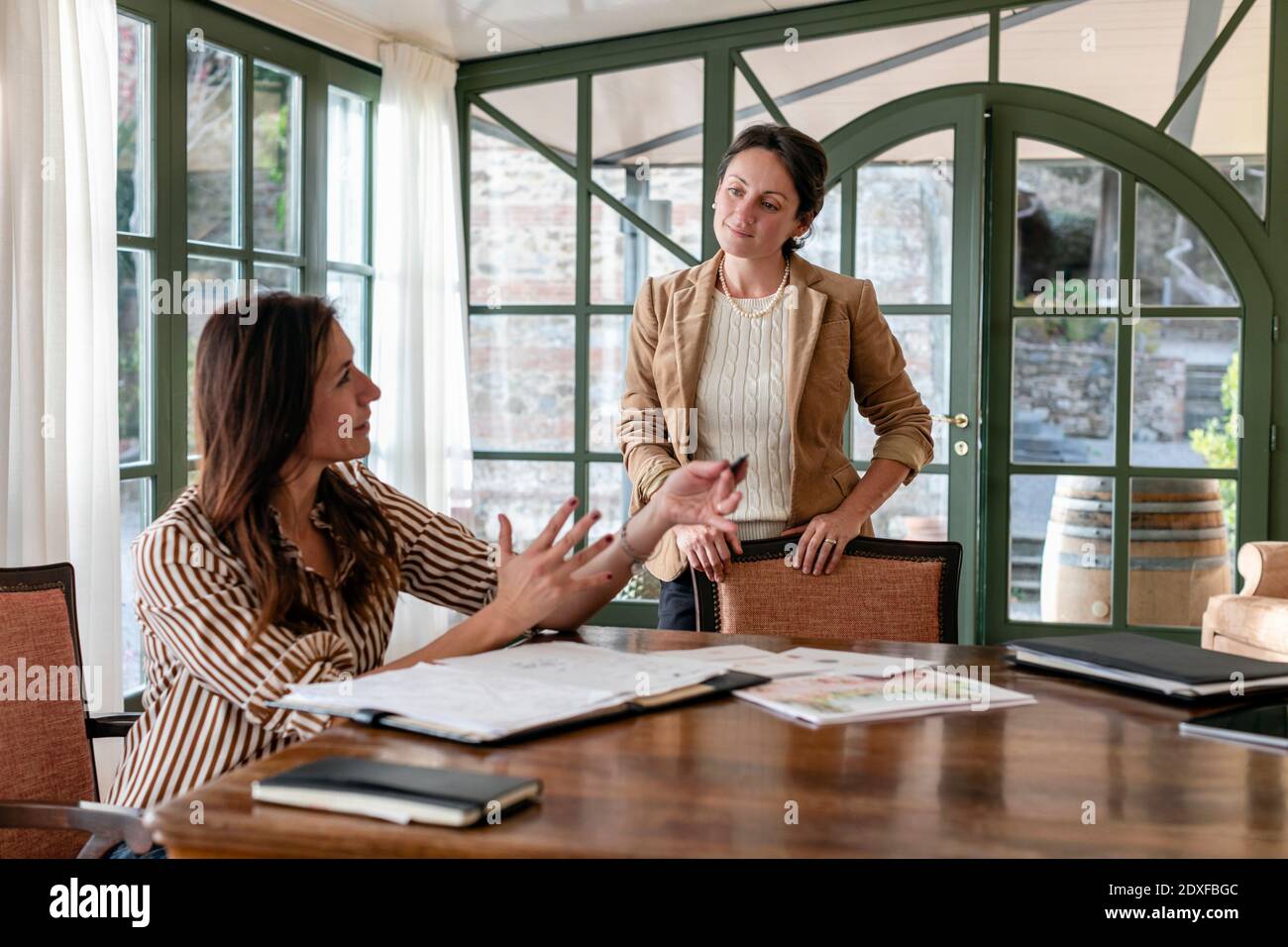 Creative female event planner discussing with colleague in meeting at ...