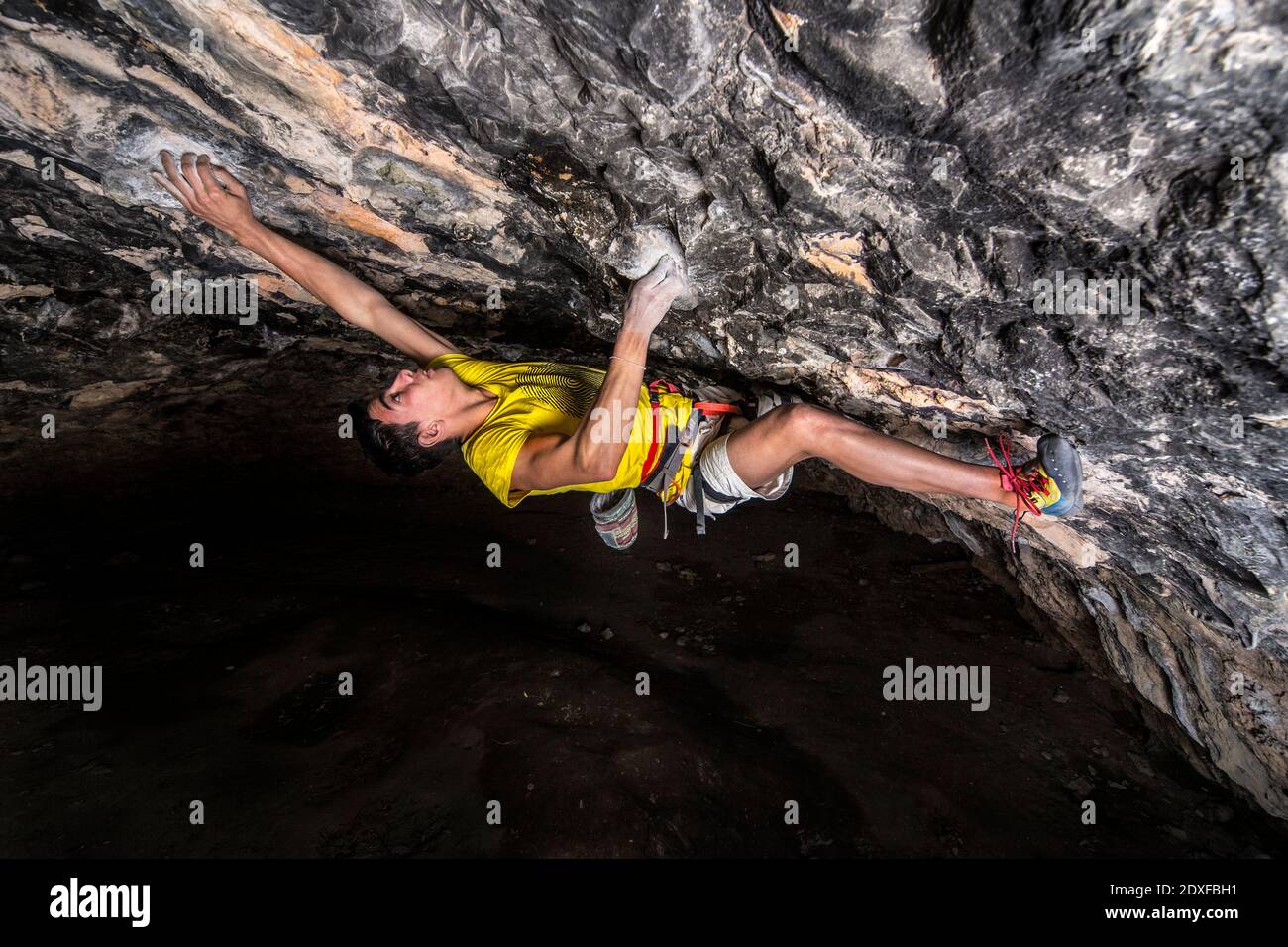 Young sportsman climbing rock in cave Stock Photo - Alamy