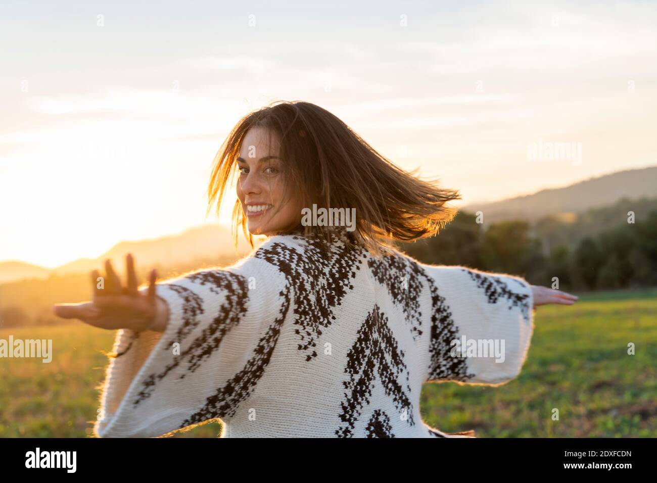 Cheerful young woman dancing with arms outstretched during sunset Stock ...