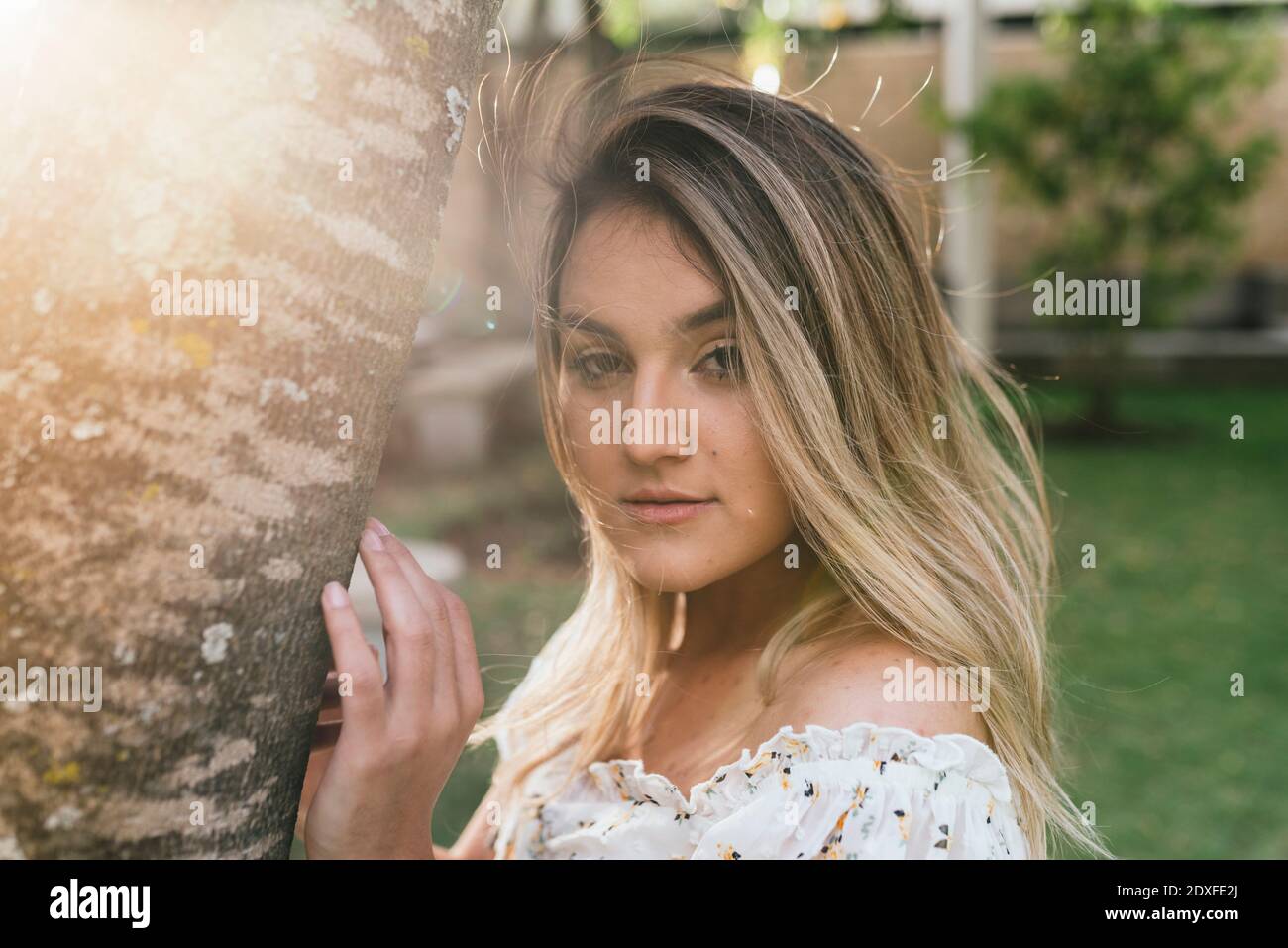 Thoughtful beautiful woman standing by tree at back yard Stock Photo ...