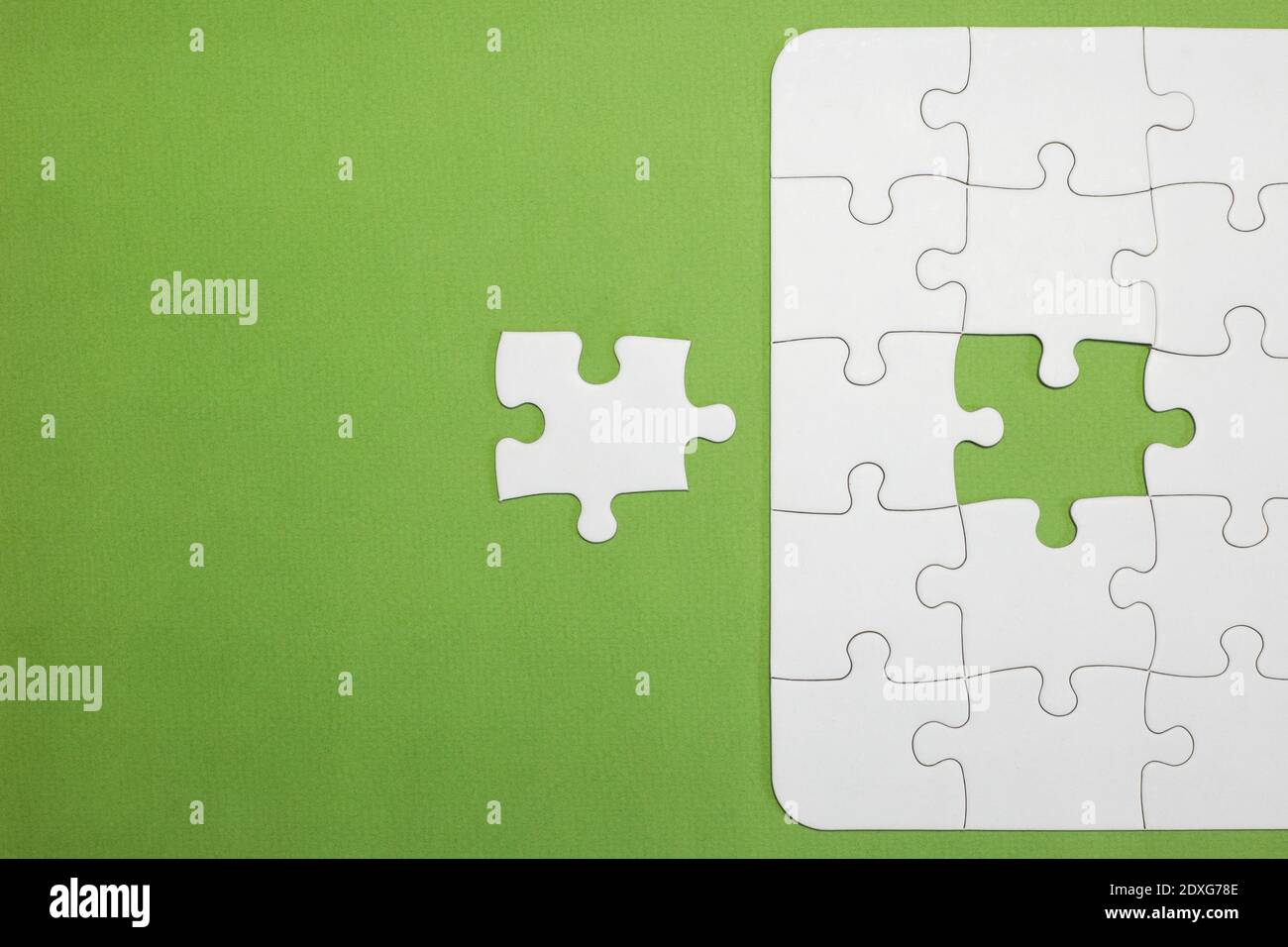 A incomplete white puzzle with green background. missing a piece to ...