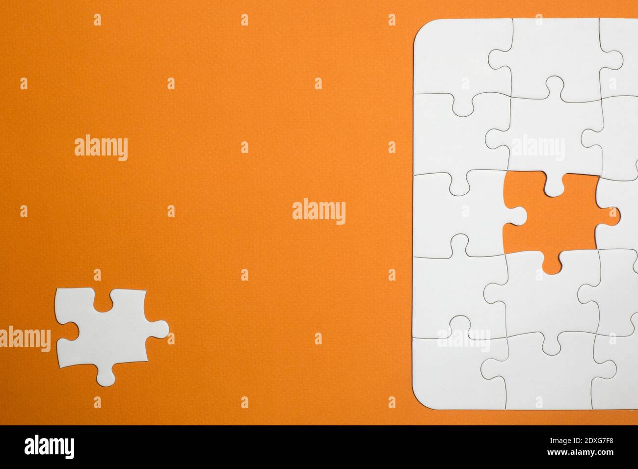 A incomplete white puzzle with orange background. missing a piece to ...