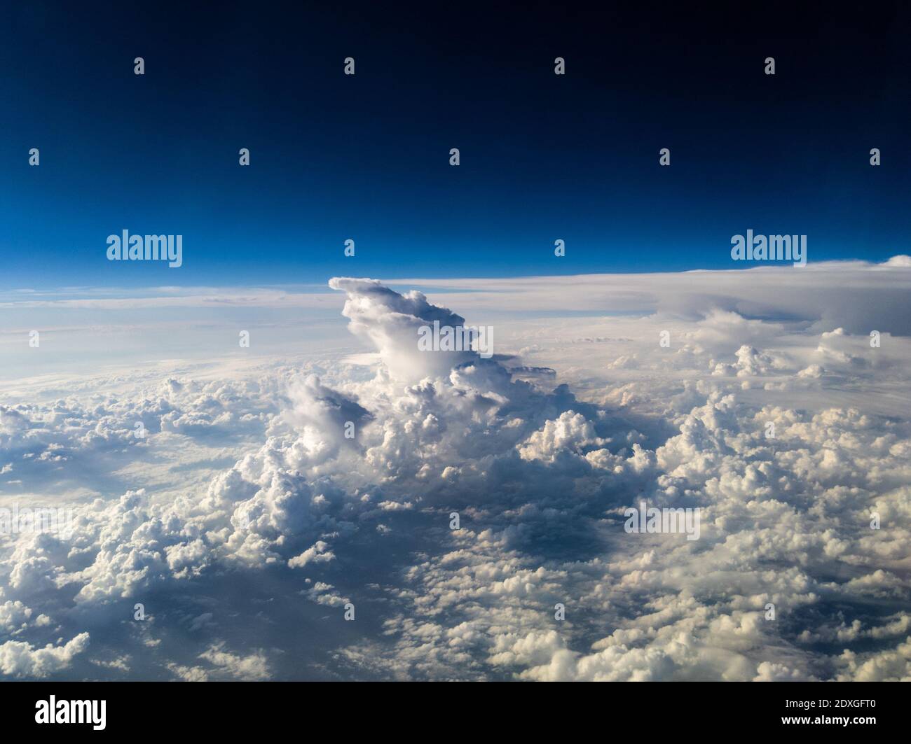 Aerial view of uniquely shaped white cumulonimbus clouds below on dark ...