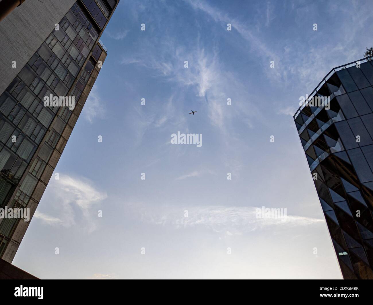 Airplane in blue sky between two skyscrapers Stock Photo - Alamy