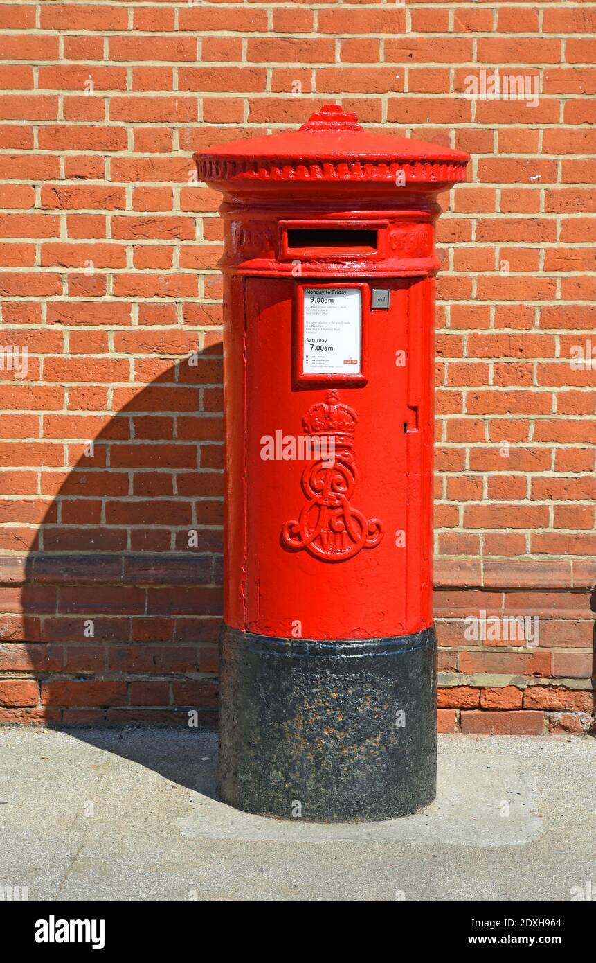 Red post box isolated against brick wall Stock Photo - Alamy