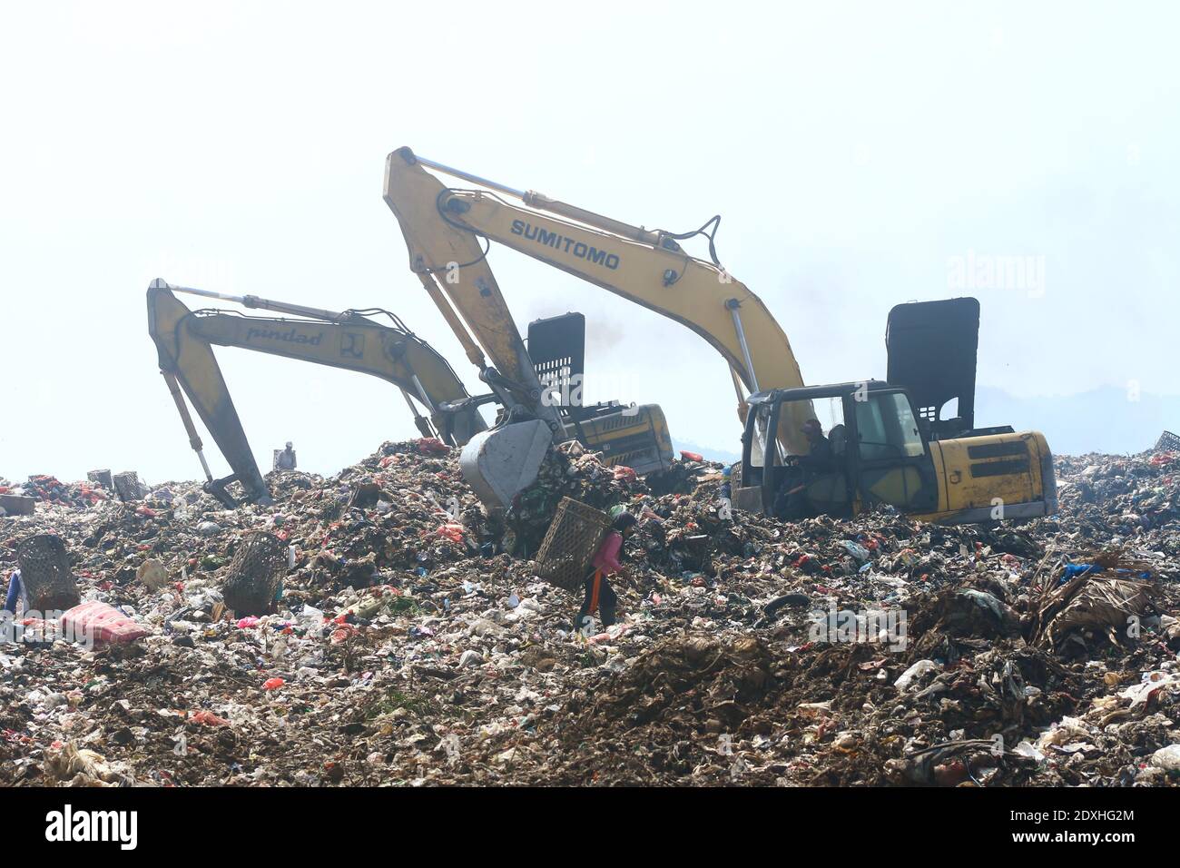 Scavengers are active in piles of rubbish in the landfill (TPA) of ...