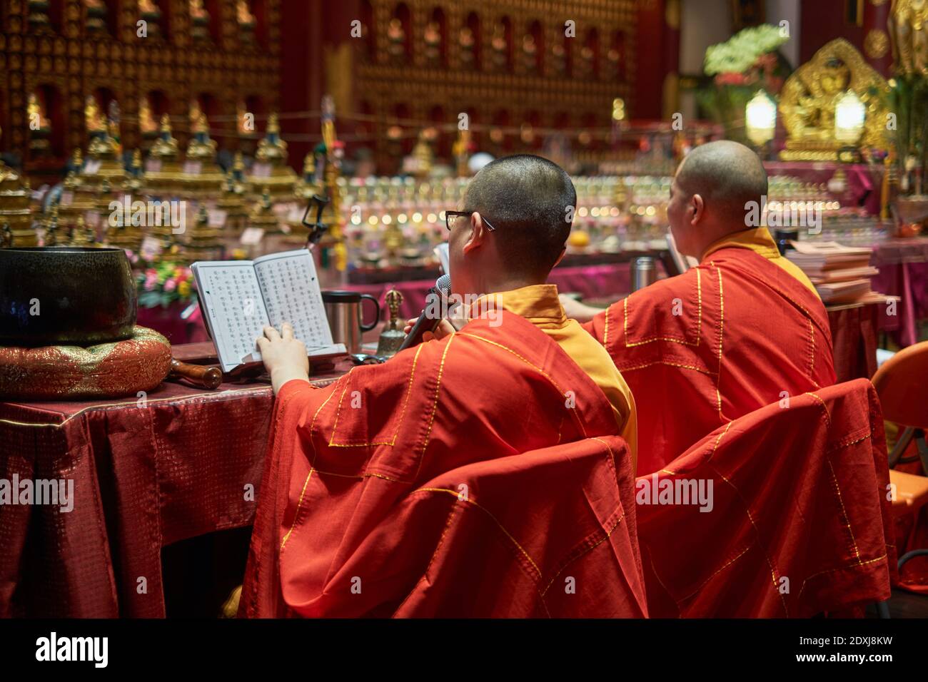 Buddhist priests reading prayers from a prayer book at the Buddha Tooth ...