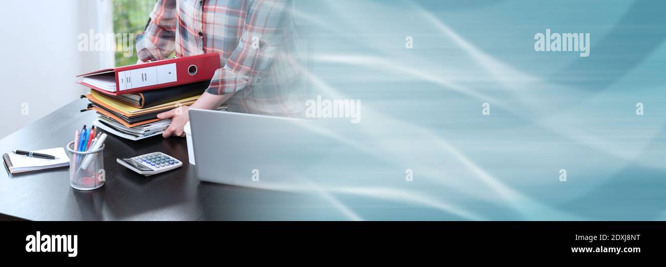 Businesswoman putting a stack of binders and folders on her desk ...