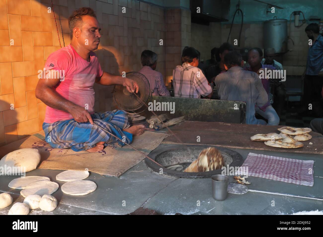A baker in a small Muslim restaurant in Mumbai, India, baking rotis ...