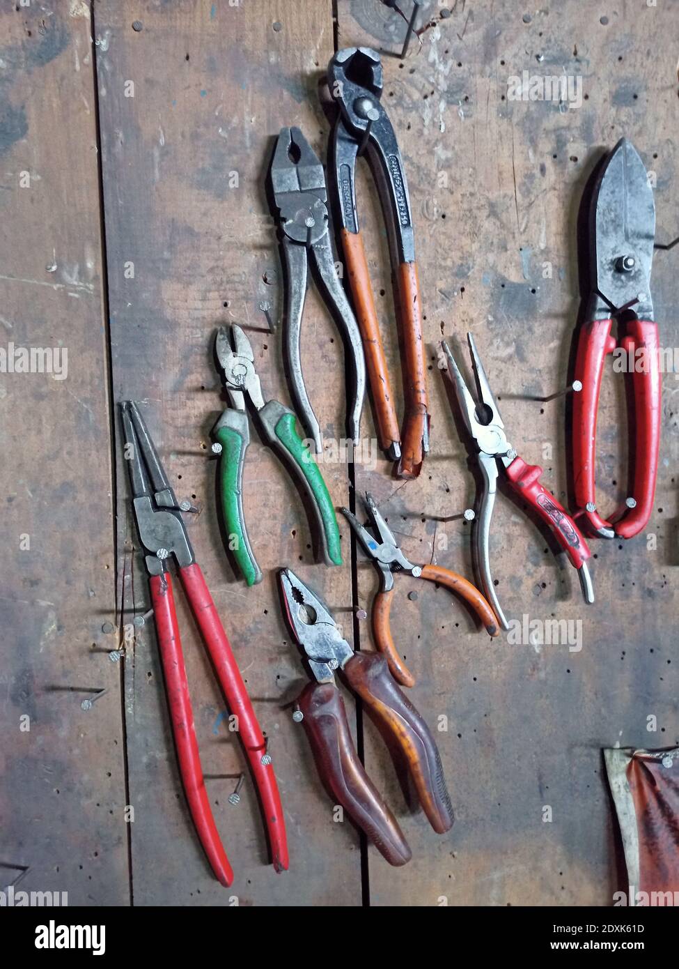 A vertical shot of different modern pliers laying on the old wooden ...