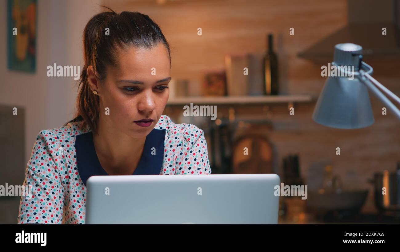 Tired business woman reading reports sitting in front of laptop late at night working from home ...