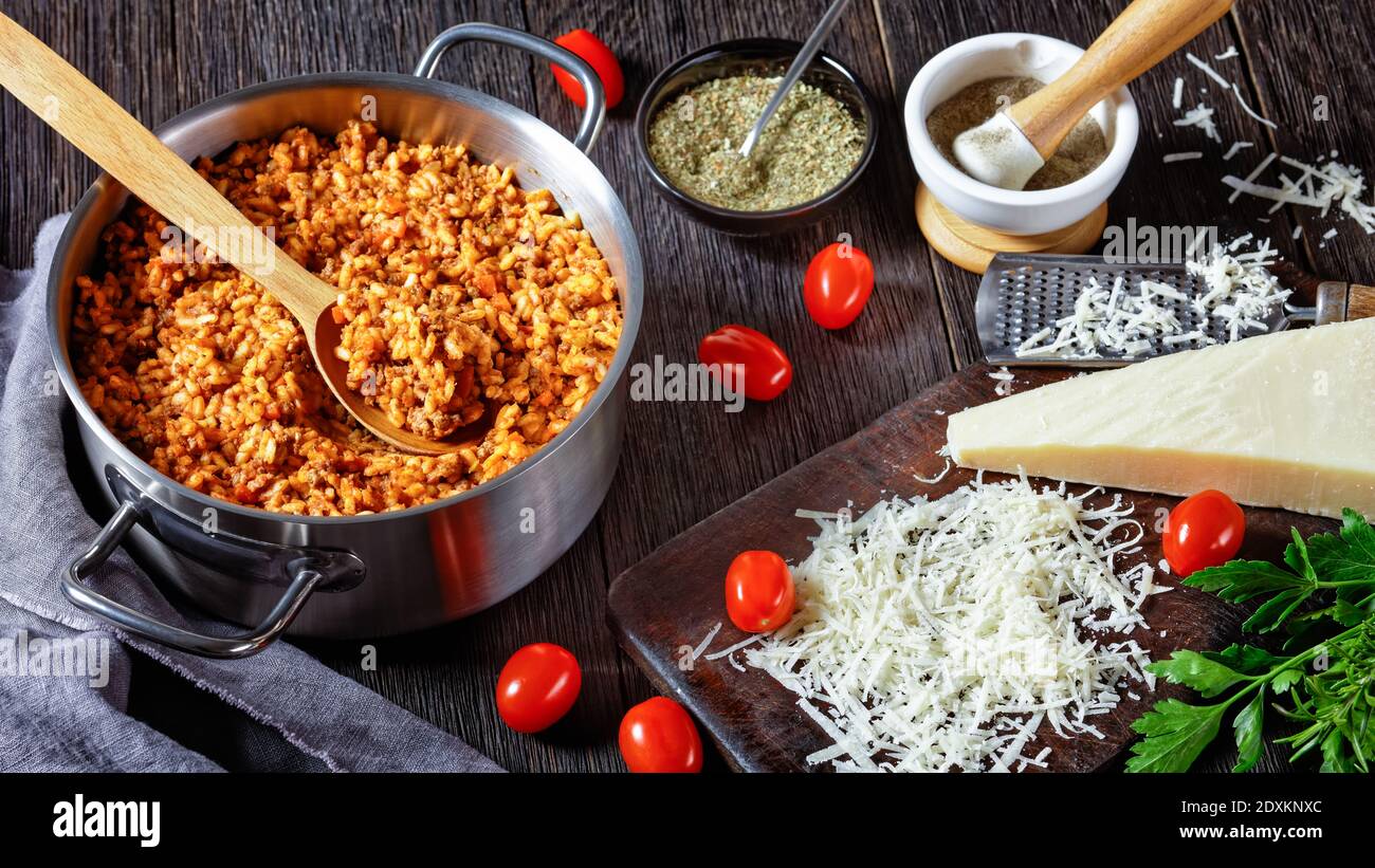 ground beef risotto bolognese in a metal stewpot with a spoon on a dark ...
