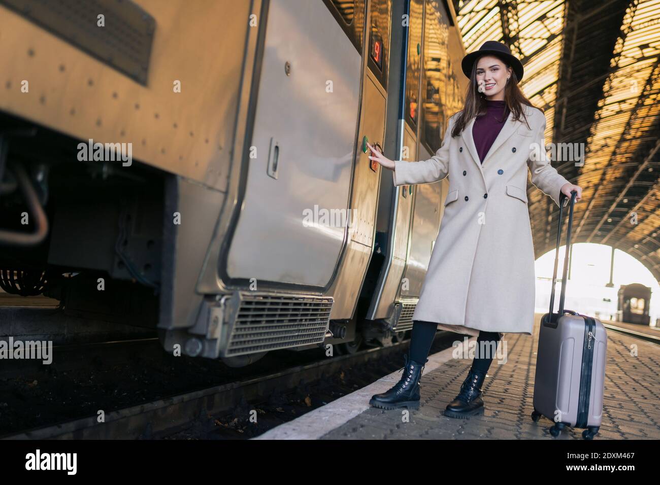 Cheerful woman presses button on the train door to enter. Railway trip ...