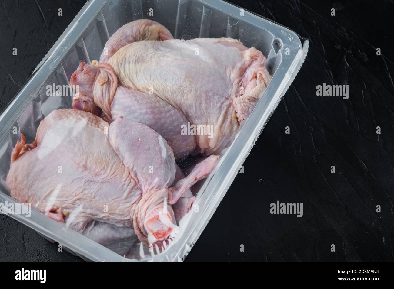 Raw chicken in plastic sealed plastic box, on black background with ...