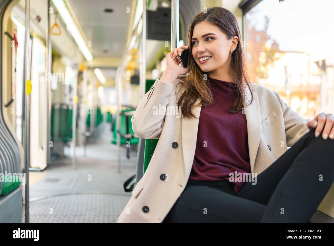 Female passenger sits on the tram and talks to the phone. Pretty ...