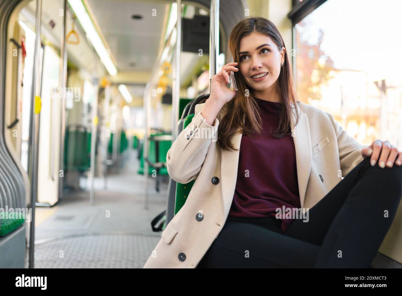 Female passenger sits on the tram and talks to the phone. Pretty ...