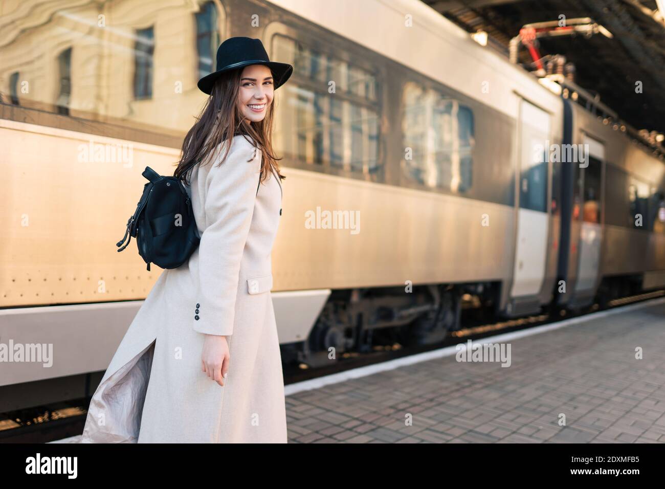 Beautiful girl tourist rushes to the train. Young cheerful woman walks ...