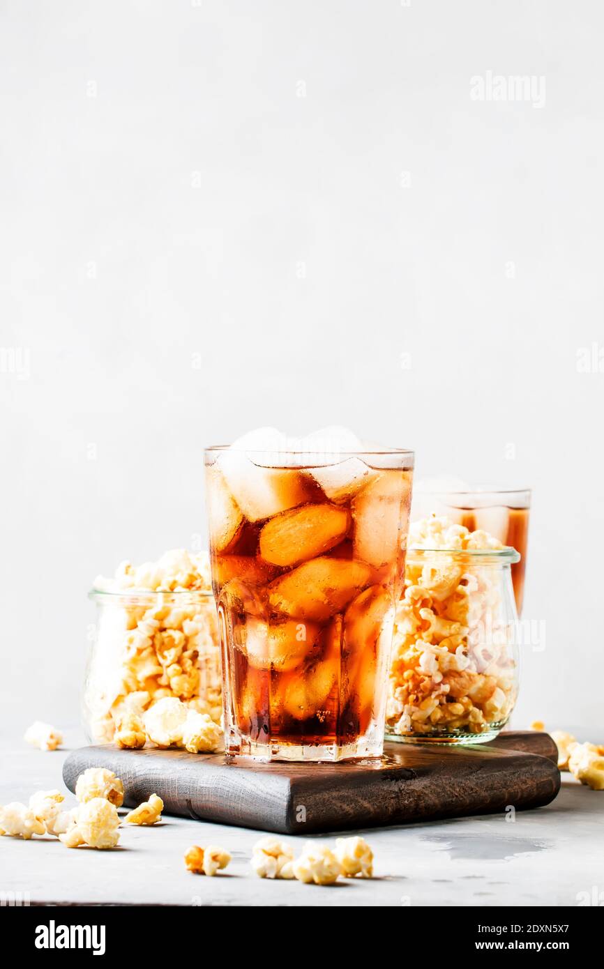 Sweet soda with ice cubes and caramel popcorn, gray background ...