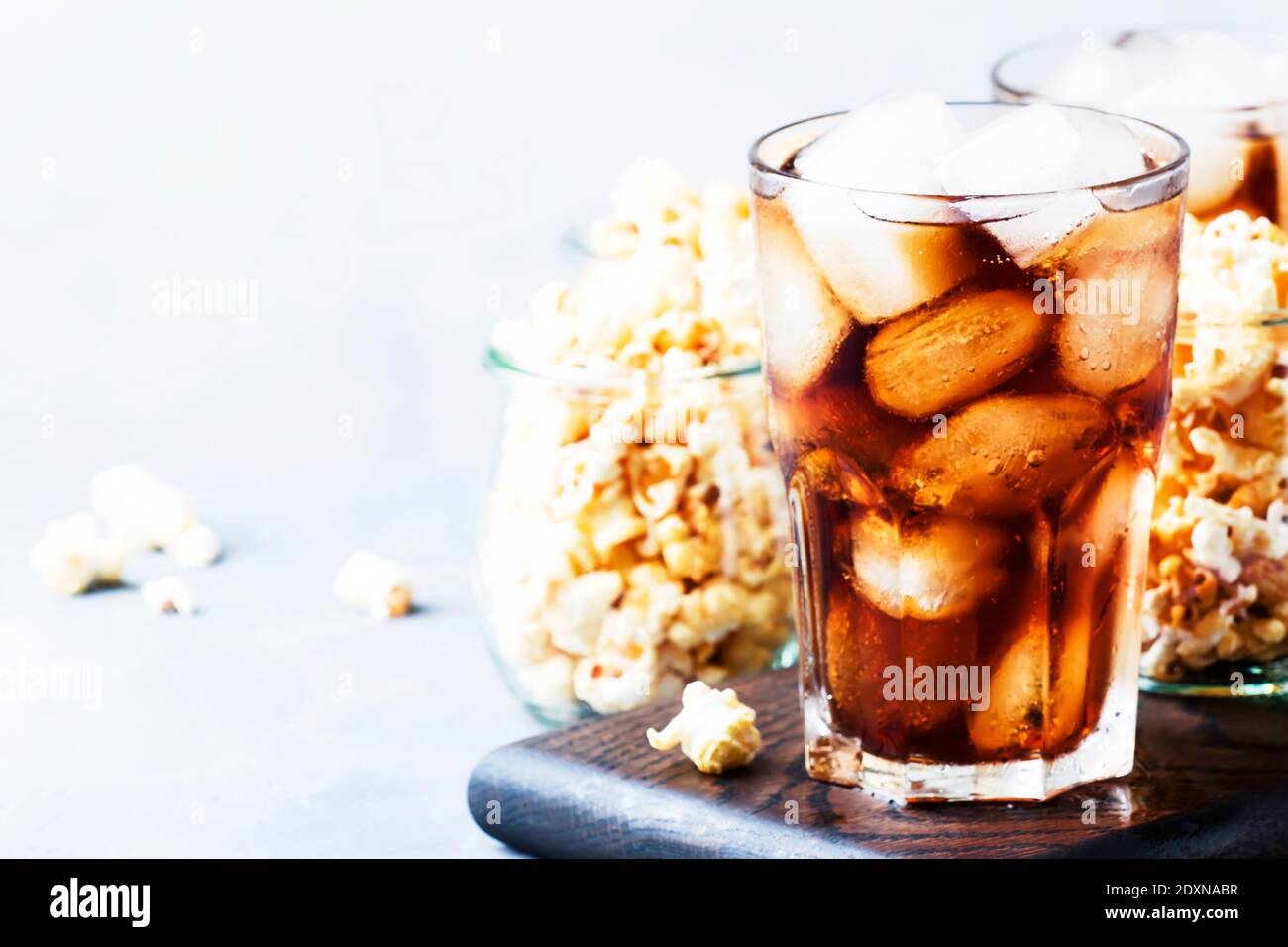 Sweet soda with ice cubes and caramel popcorn, gray background ...