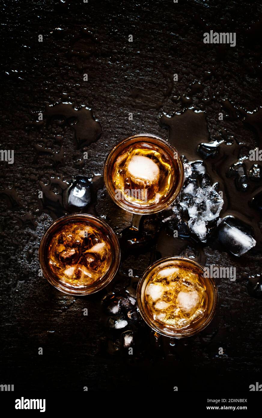 Cold whiskey in a glass with crushed ice on a black stone wet ...