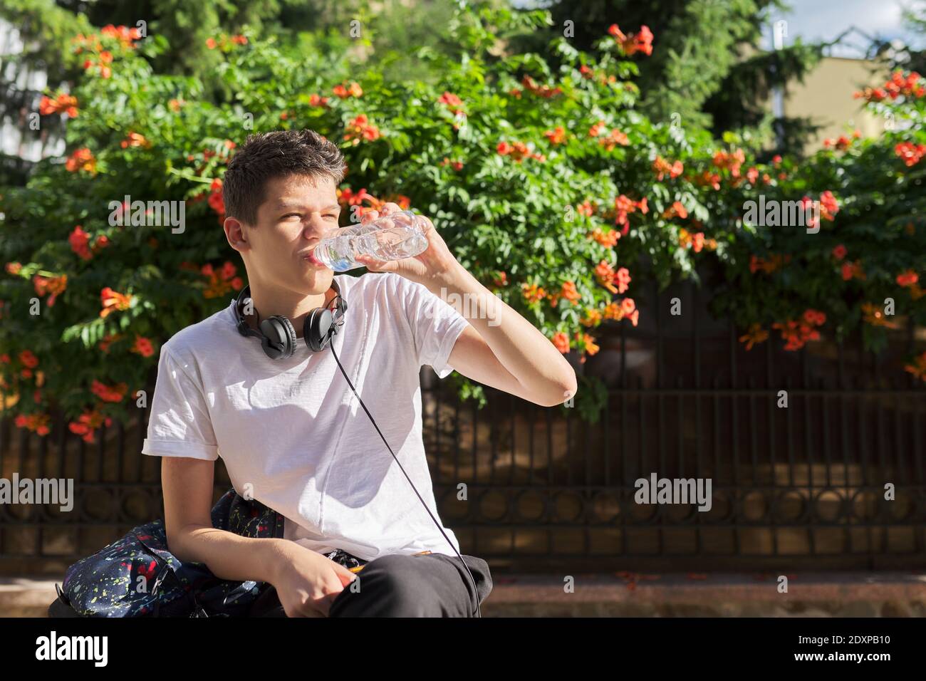 Teenager guy drinking water from bottle and removing thirst on hot ...