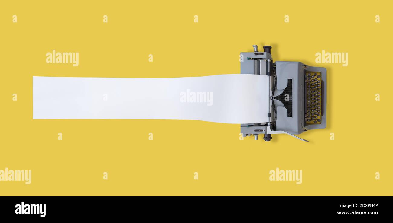 old typewriter with very long paper and yellow background with space ...