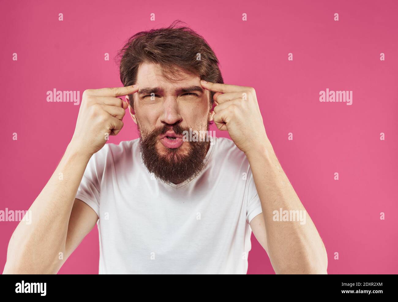 Man holds his hands near his face on a pink background stress ...