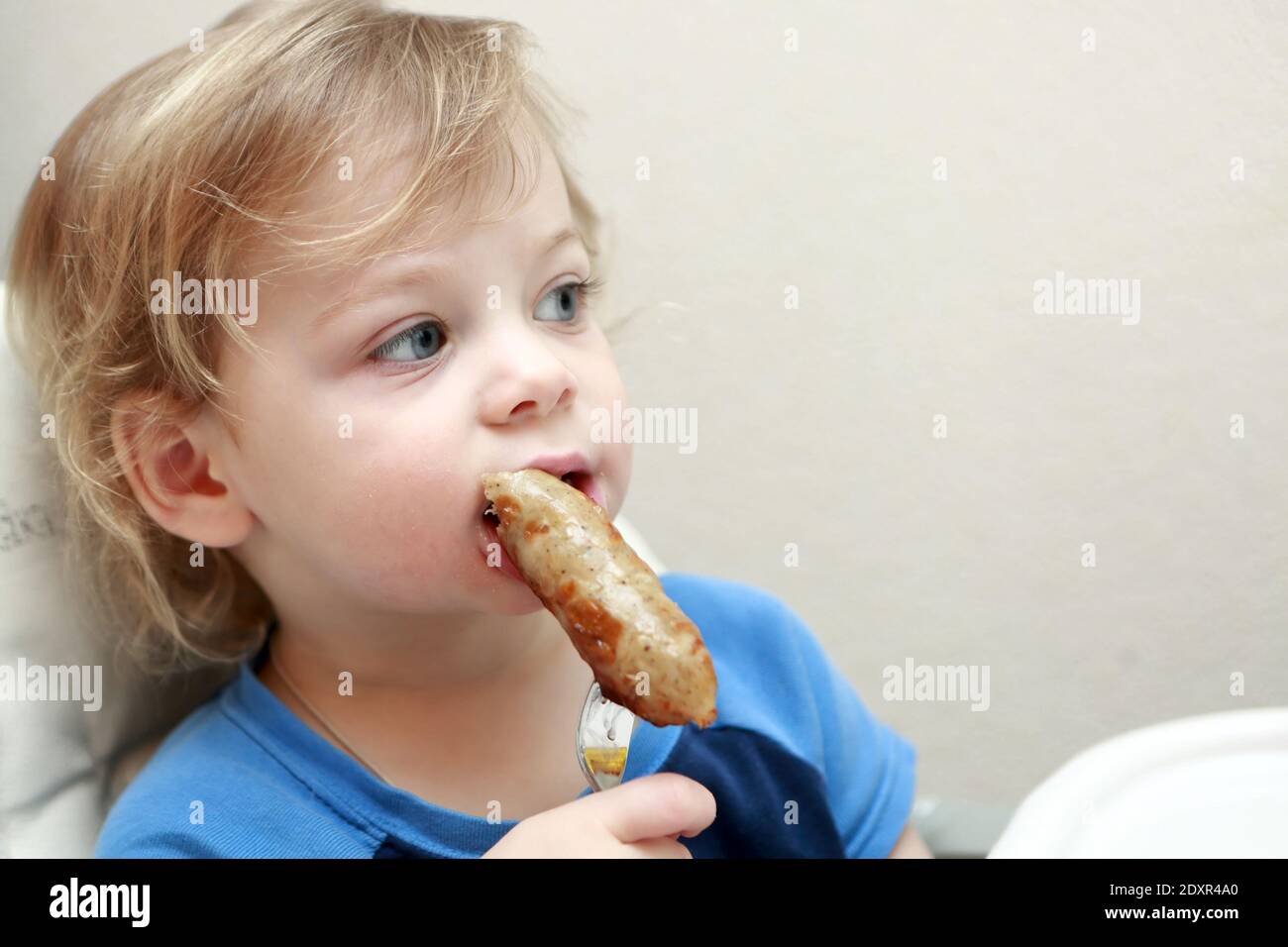 Child eating sausage in the kitchen at home Stock Photo - Alamy