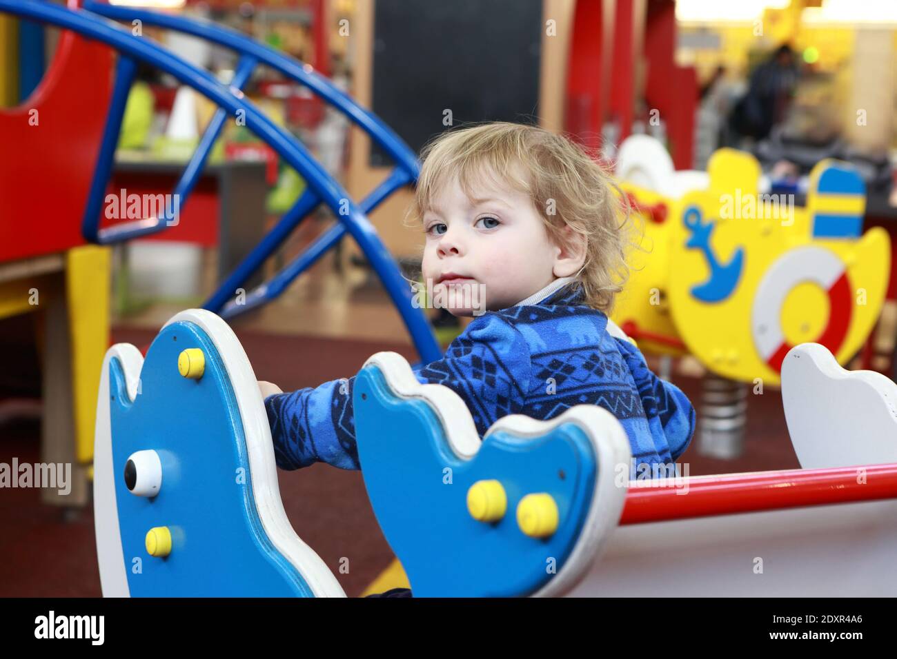 Serious child is shaking at indoor playground Stock Photo - Alamy