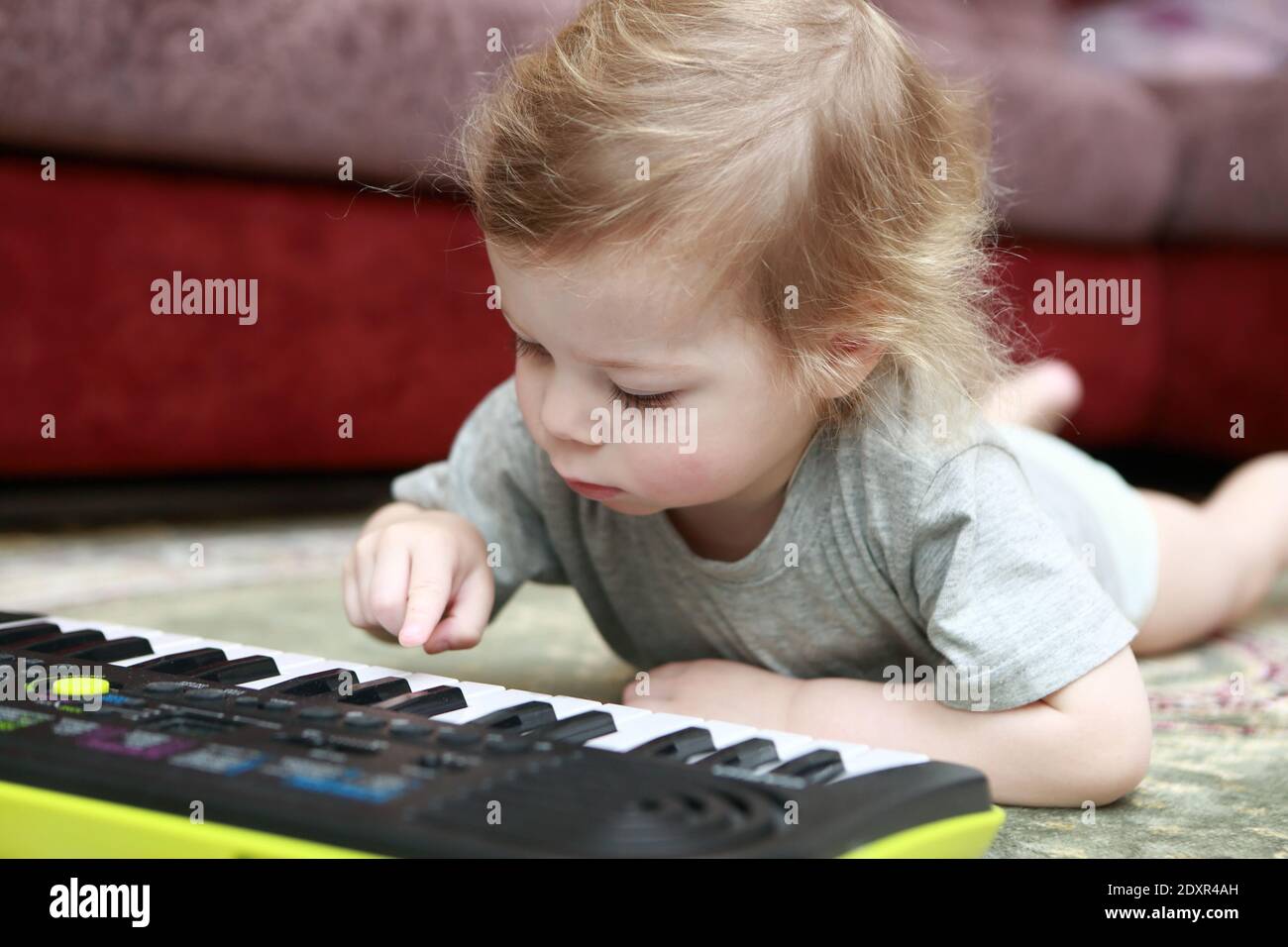 Child lying and playing on synthesizer at home Stock Photo - Alamy